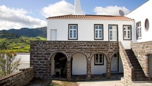 Um edifício branco com telhado telhado, arcos de pedra e uma escadaria.