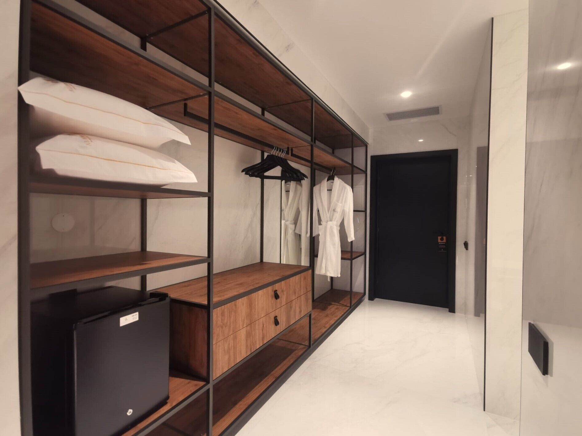 Um closet moderno com prateleiras abertas, cômoda de madeira e unidade de armazenamento preta.