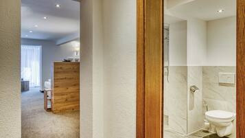 Casa de banho moderna com chuveiro, sanita e pavimento em mármore.