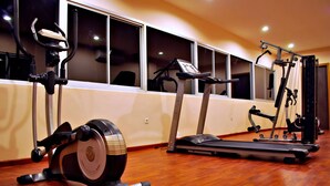 Uma academia doméstica com equipamentos de ginástica, incluindo esteira, elíptico e bicicleta ergométrica.