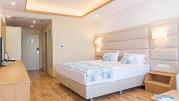 Quarto de hotel moderno com uma cama grande, abajures, uma escrivaninha de madeira e um guarda-roupa embutido.