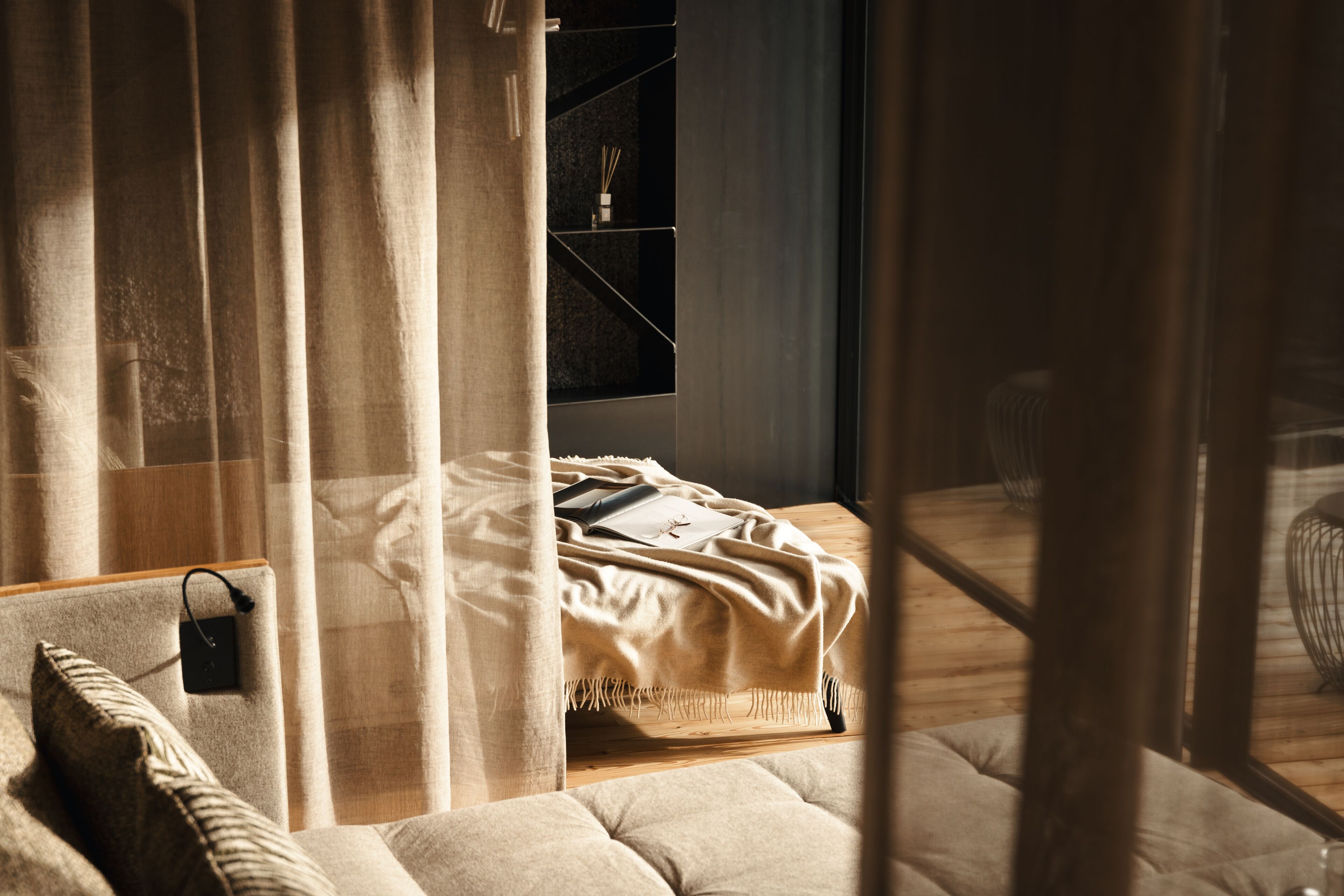 Um quarto com uma cama, mesa de cabeceira, abajur e janela com cortinas.