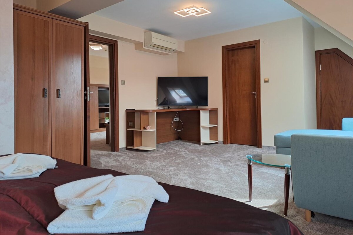 Quarto de hotel com cama, televisão, escrivaninha e cadeira.