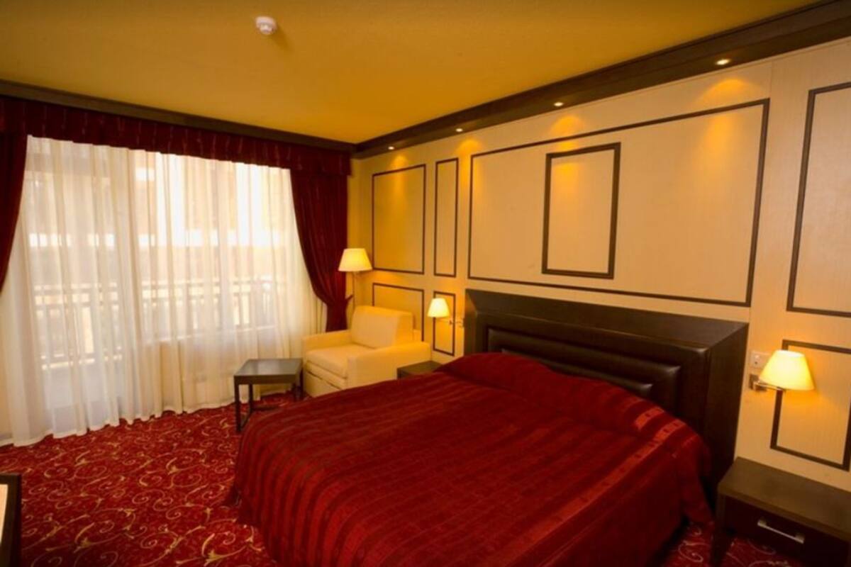 Quarto de hotel com uma cama grande, uma cadeira, uma mesa de cabeceira e um abajur.