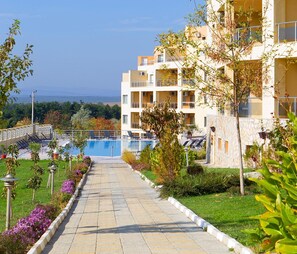 Um hotel com piscina, um caminho no jardim e vista para o mar.