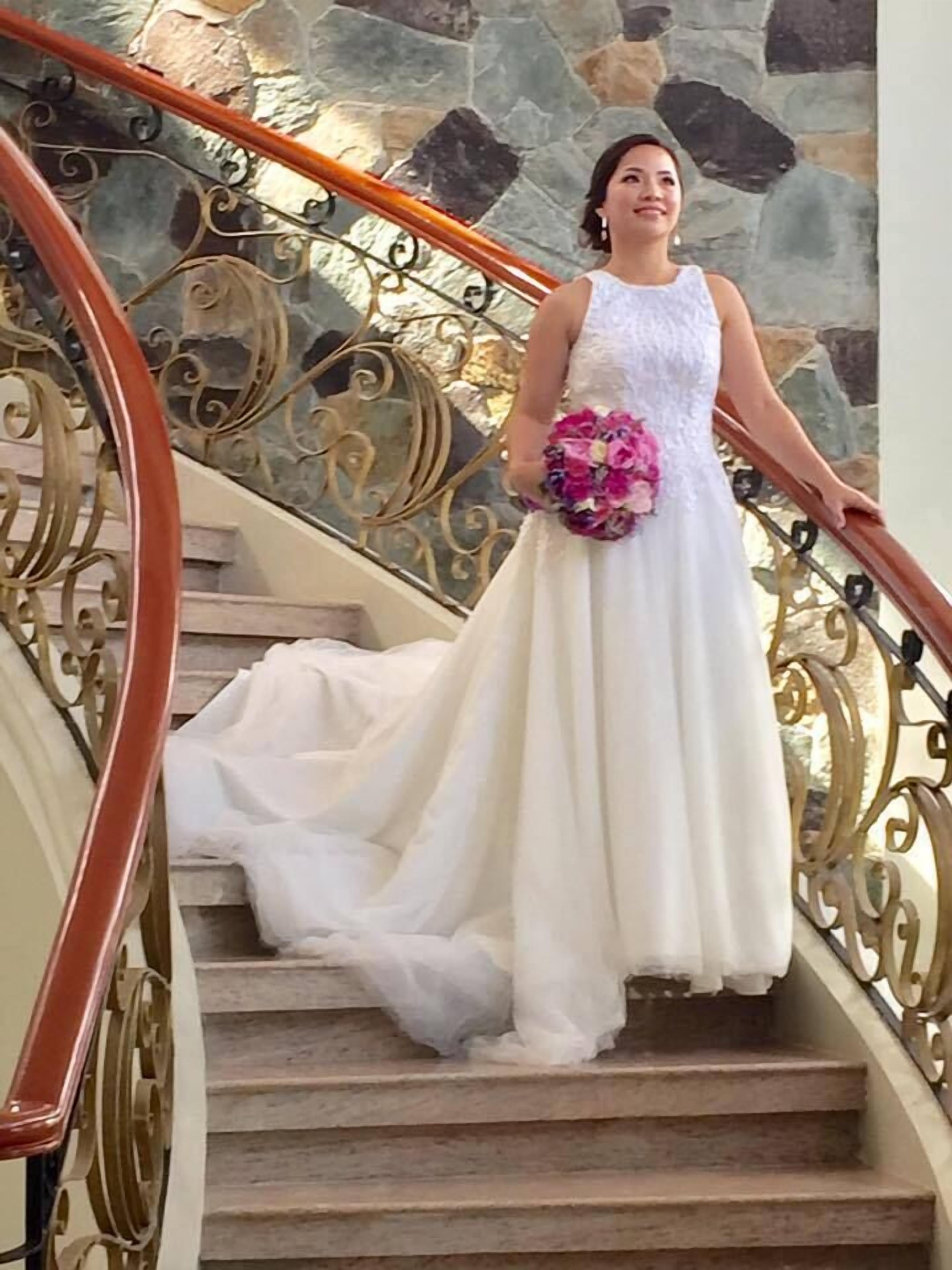 Uma noiva num vestido de casamento branco desce uma escadaria de pedra com grades de metal ornamentadas.