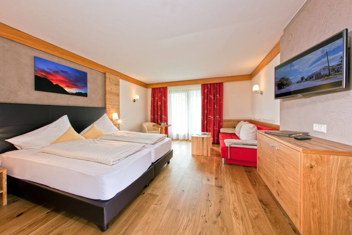 Quarto de hotel com uma cama grande, uma escrivaninha, uma cadeira e uma televisão.