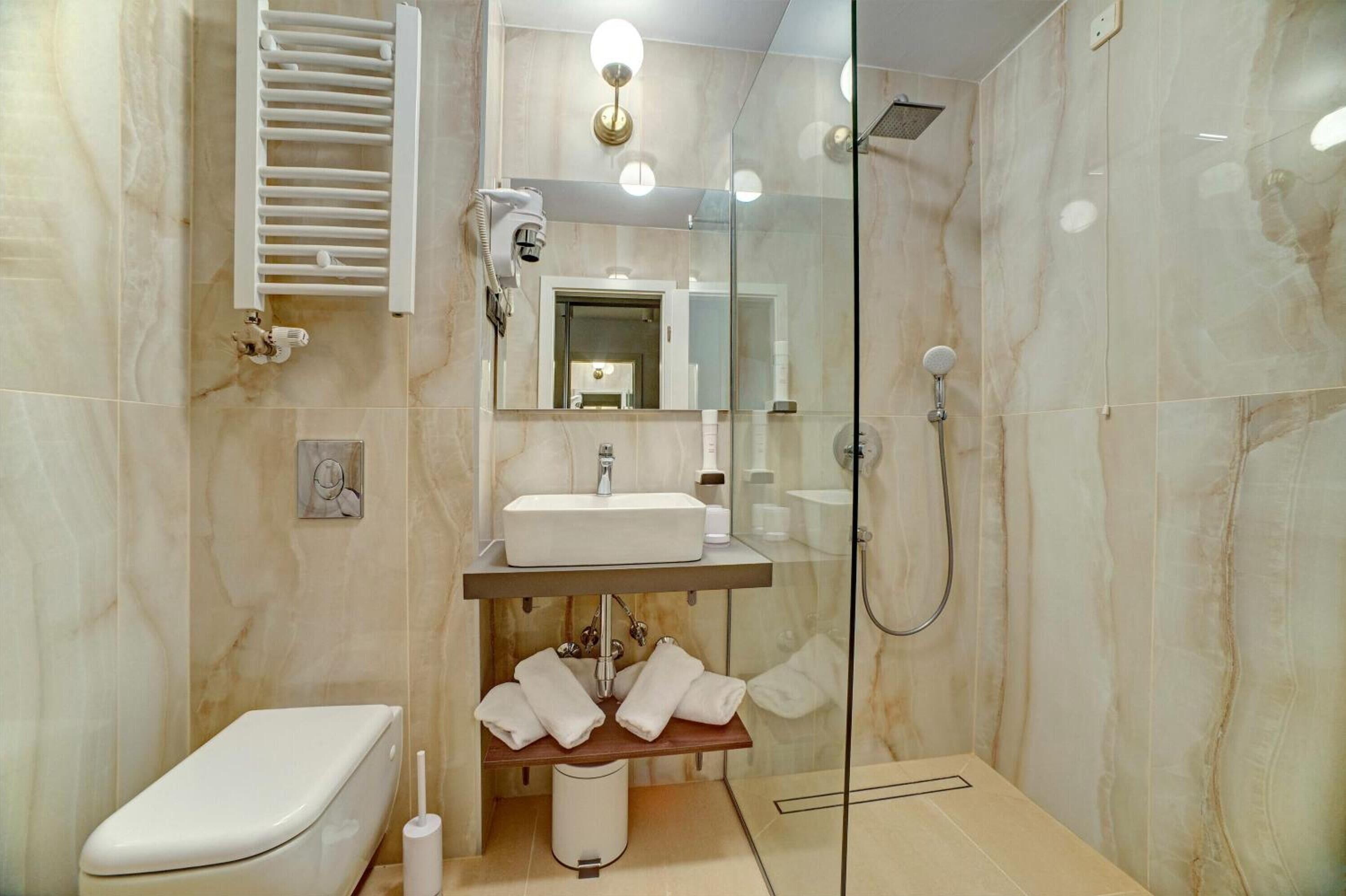 Casa de banho moderna com cabine de duche em vidro, lavatório branco e sanita.