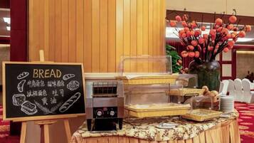 Disposição de buffet com pães, uma torradeira e diversos recipientes de comida sobre uma mesa.