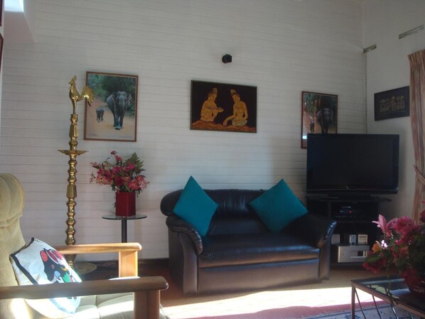 Uma sala de estar com sofá, televisão e obras de arte penduradas na parede.