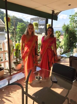 Duas pessoas vestindo trajes tradicionais em uma área externa coberta, com uma placa indicando "Days Inn Lodge" ao fundo.