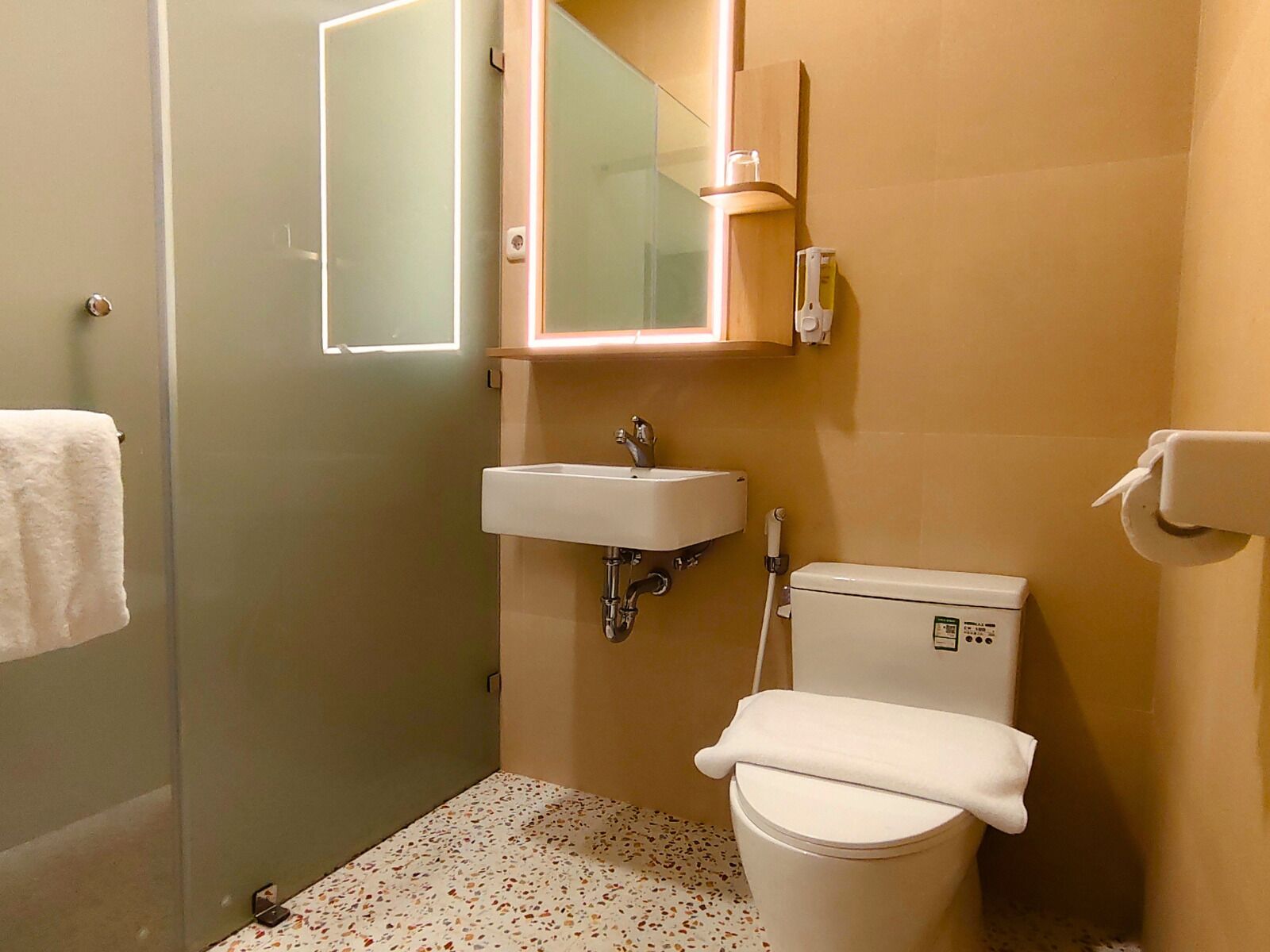 Casa de banho com sanita, lavatório e cabine de duche em vidro.