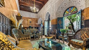 Um interior ricamente decorado com mobiliário tradicional, uma mesa de centro de vidro e uma grande janela de vitrais.