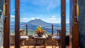 Uma mesa de madeira com cadeiras e um arranjo de flores em um quarto com paredes de pedra e vista para uma montanha.