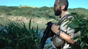 Uma pessoa à beira da água, segurando uma arma de fogo.