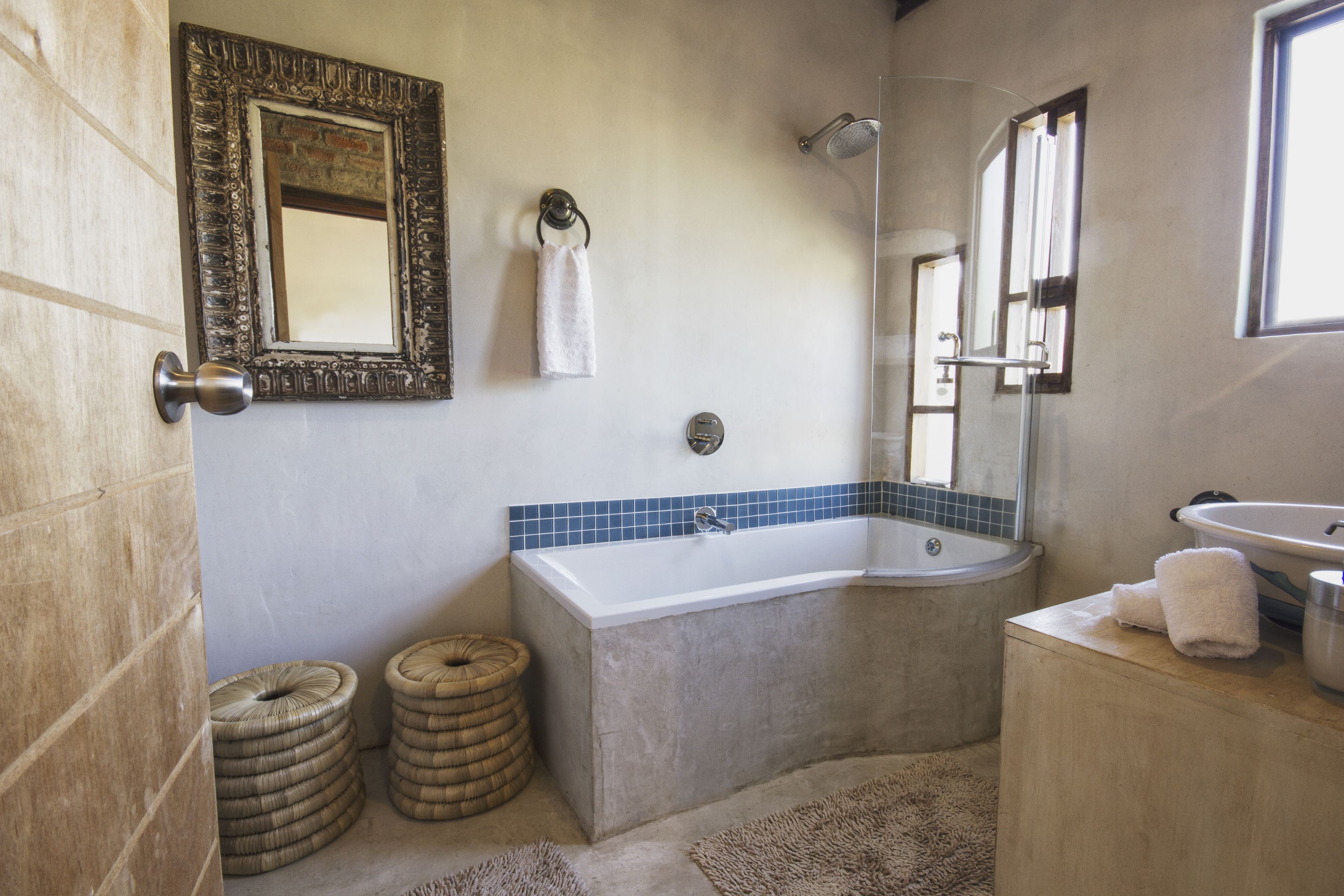 Casa de banho com banheira, lavatório, espelho e porta-toalhas.
