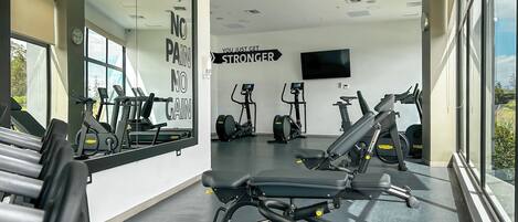 Uma academia com equipamentos de ginástica, um espelho grande e frases motivacionais na parede.