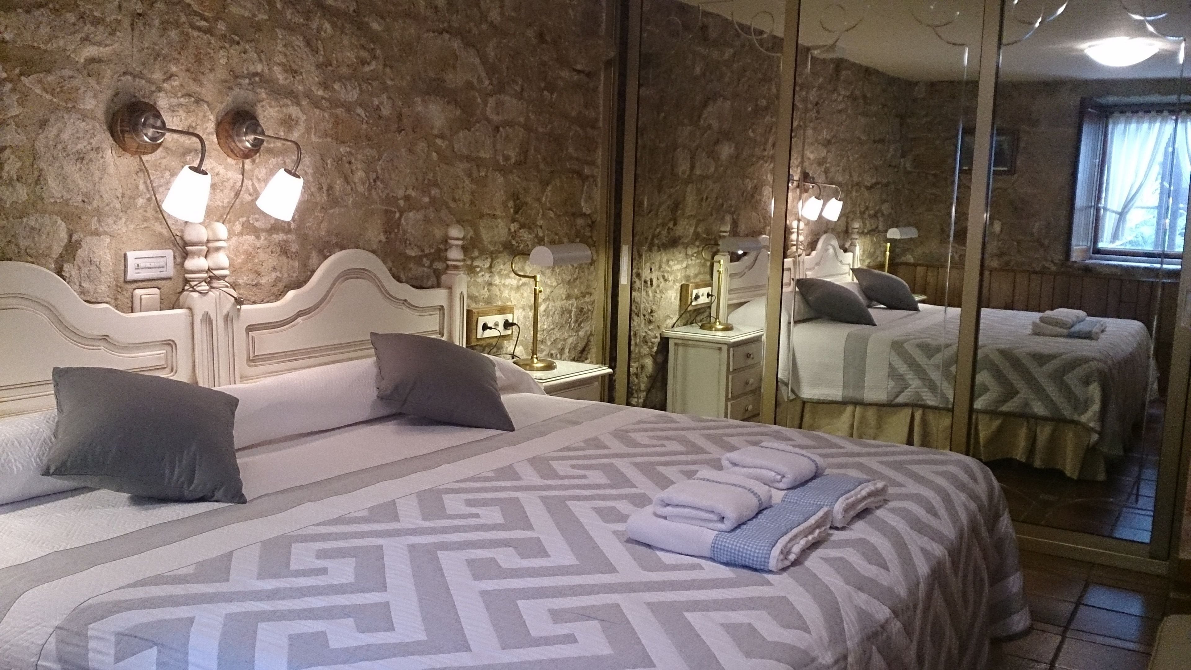Quarto com uma cama grande, um espelho e uma parede de pedra.