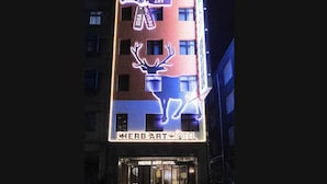Hotel com um letreiro de neon que apresenta um veado e notas musicais, possivelmente indicando um tema ou marca.