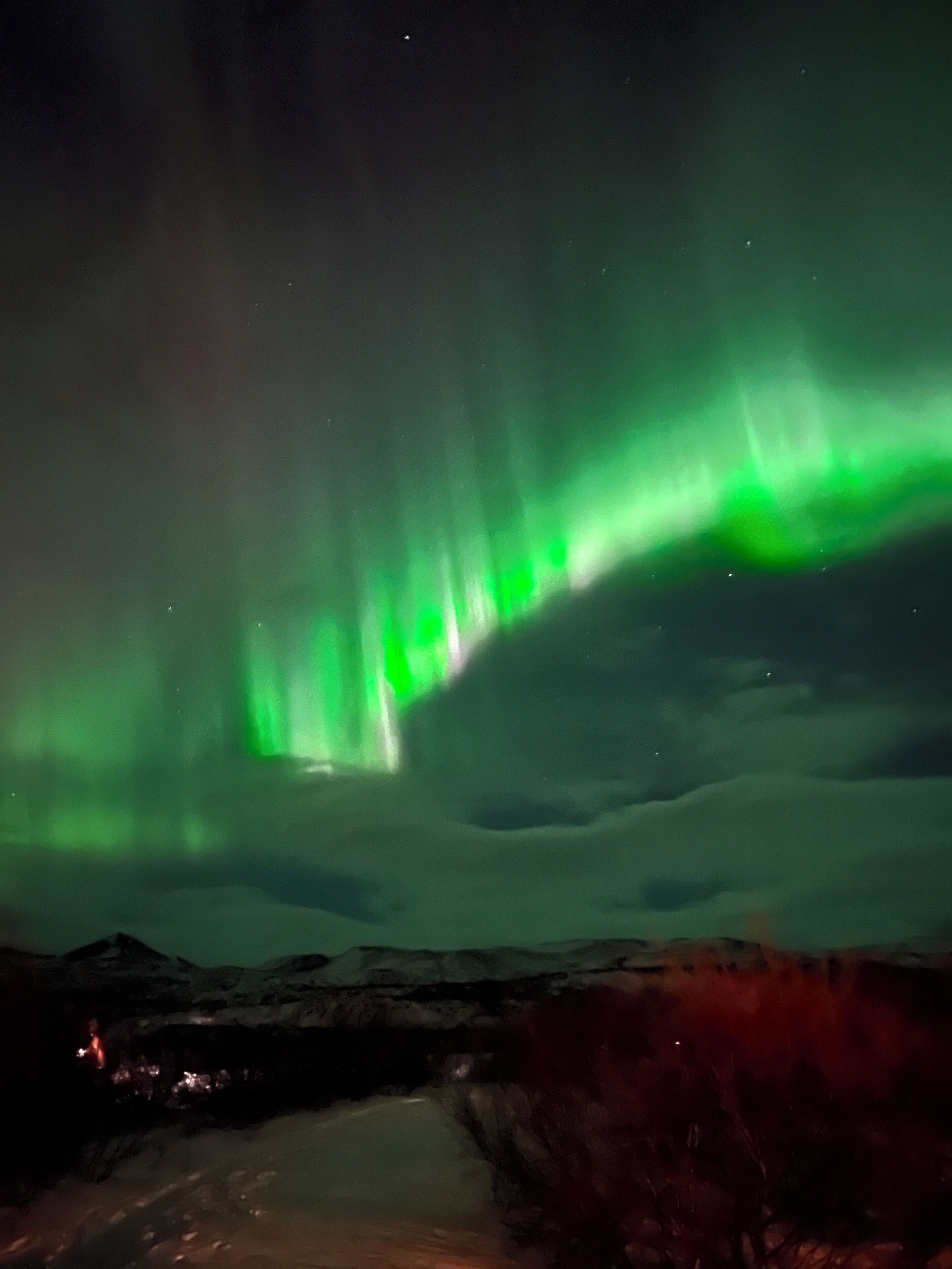 Céu noturno com aurora boreal verde sobre paisagem nevada.