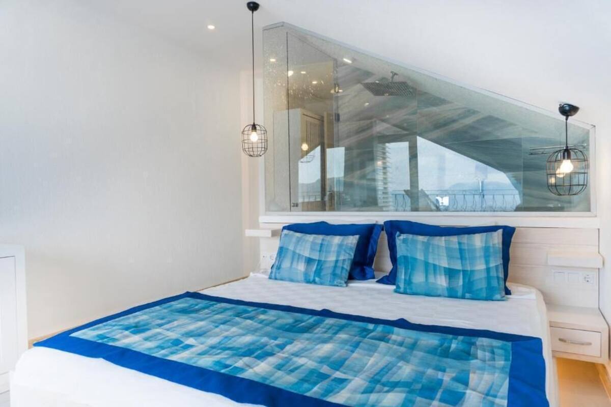 Um quarto moderno com uma cama grande, uma janela com vista e luminárias pendentes.