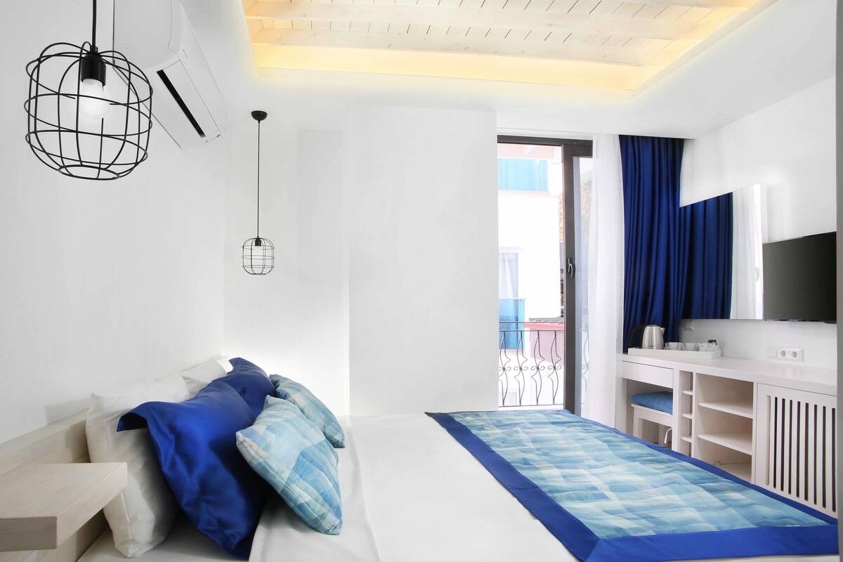 Quarto com cama, televisão, guarda-roupa e varanda.