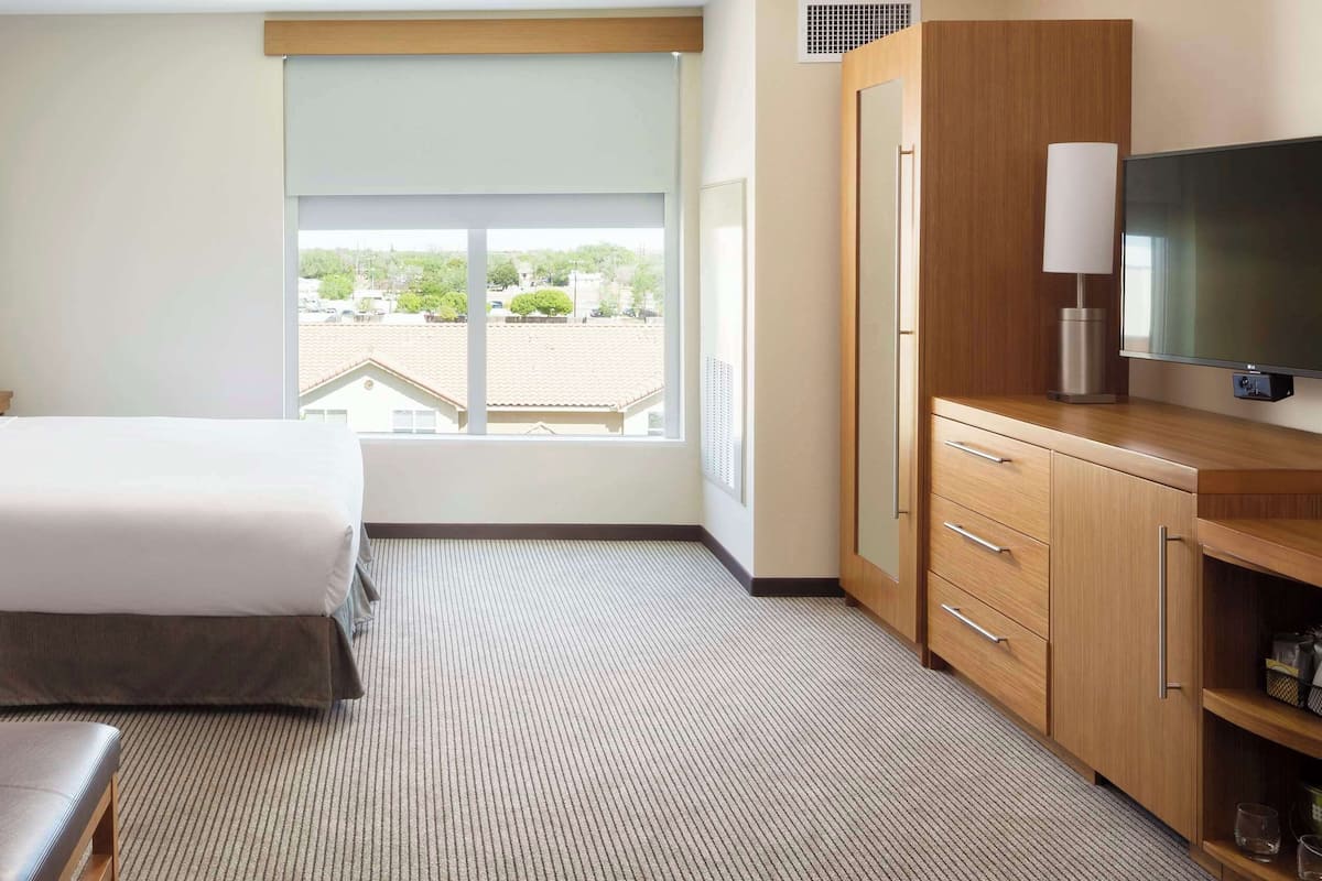 Quarto de hotel com cama, sofá, televisão e vista para o exterior.
