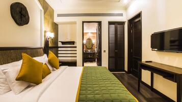 Quarto de hotel com cama, televisão, escrivaninha e espelho.