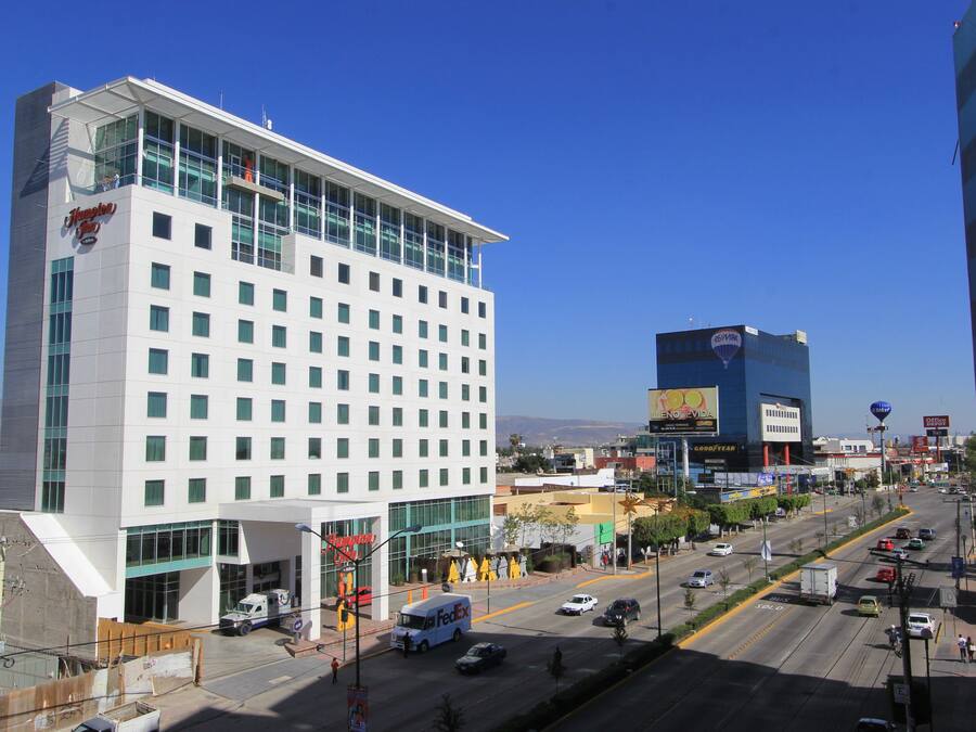 Um hotel moderno com fachada de vidro ampla, vários andares e uma placa de destaque.