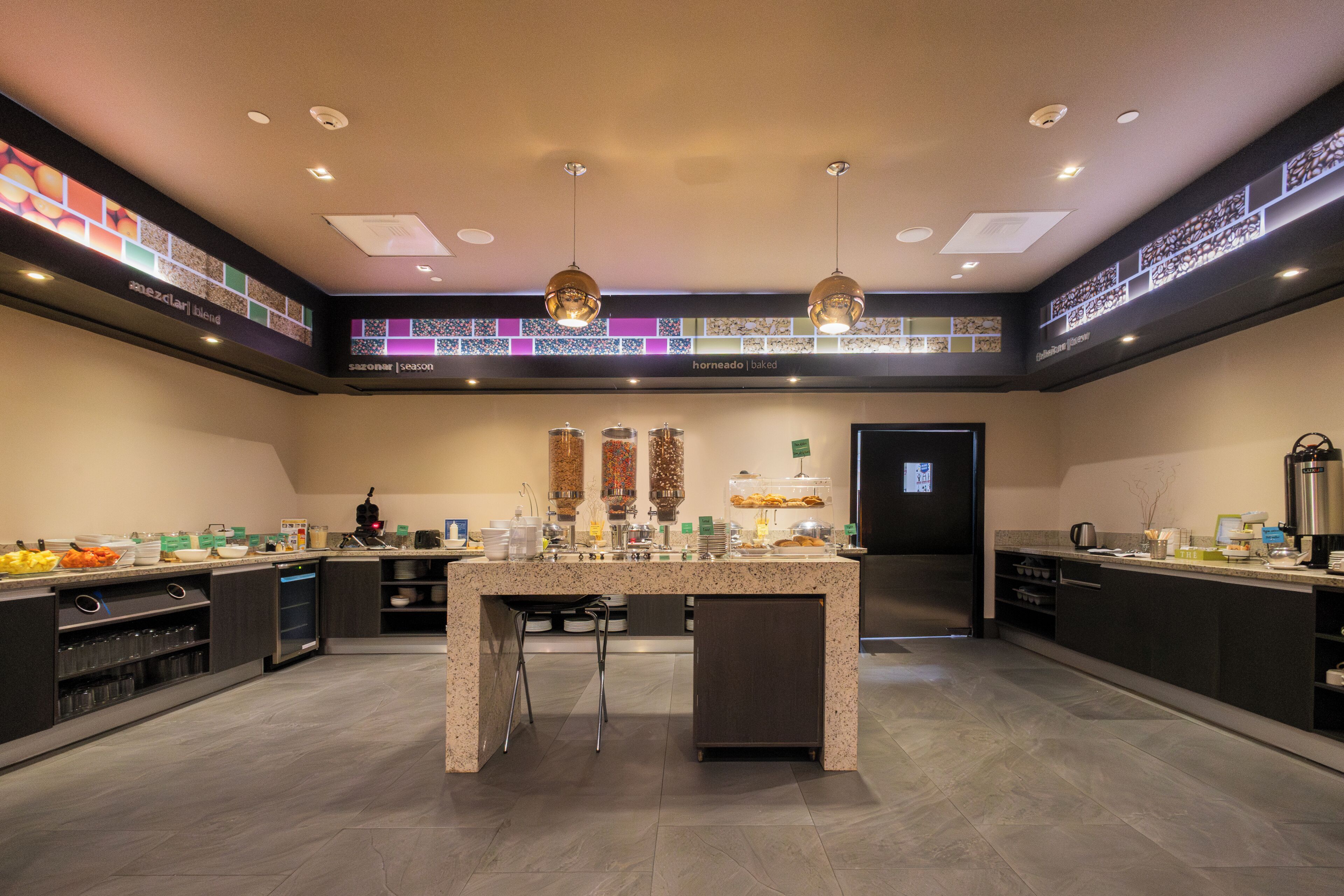 Cozinha moderna com ilha central, banquetas de bar e diversos alimentos à mostra.