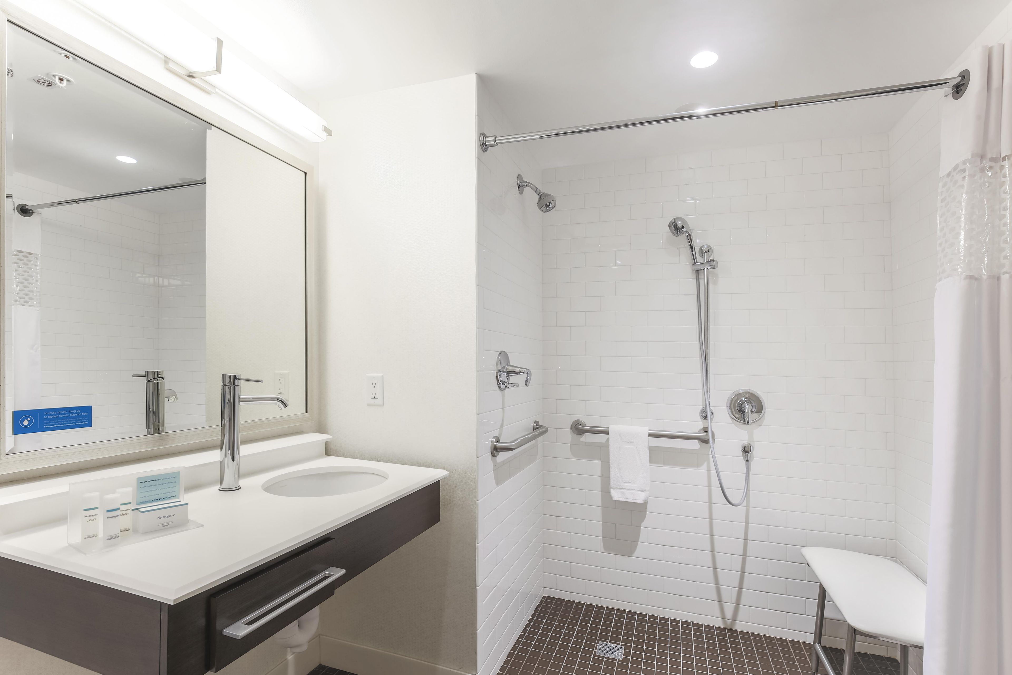 Uma casa de banho moderna com lavatório branco, espelho e chuveiro.
