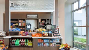 Um balcão de loja com diversos snacks e bebidas, uma máquina de café e um aviso indicando que serve café fresco moído na hora.