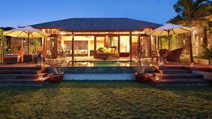 Uma casa moderna com piscina, área de estar externa e um pátio bem iluminado.