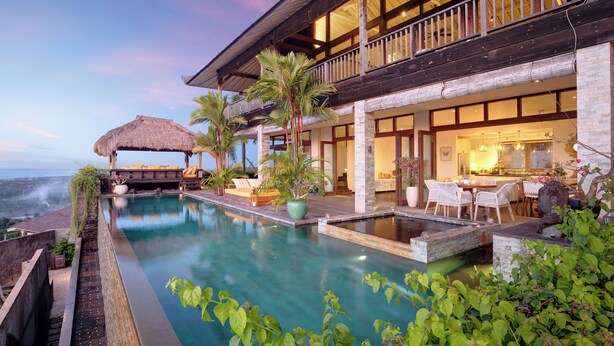 Um resort luxuoso com piscina infinita, área de refeições e vista para o oceano.