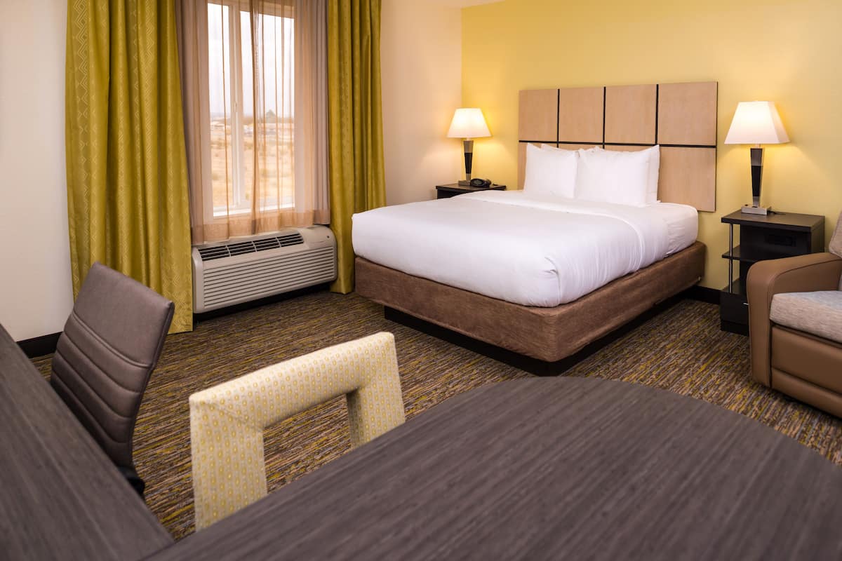 Quarto de hotel com uma cama grande, duas mesas de cabeceira com luminárias, uma escrivaninha e uma cadeira.