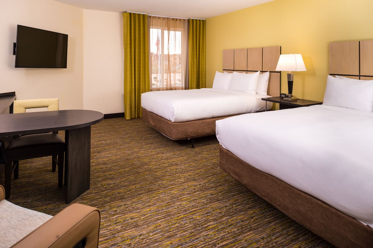 Quarto de hotel com duas camas, televisão, escrivaninha e cadeira.