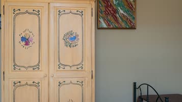 Um quarto com uma cama, um guarda-roupa com desenhos florais e uma pintura abstrata colorida na parede.