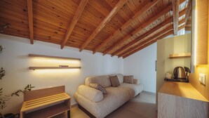Um quarto aconchegante com teto de madeira, um sofá, um banco e uma pequena mesa com uma chaleira.