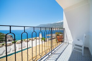 Uma varanda com vista para o mar, uma piscina e uma cadeira.