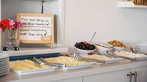 Um buffet de café da manhã com diversas opções de comida e uma placa com uma mensagem.