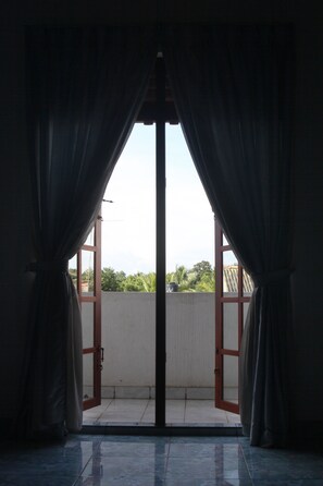 Quarto com porta de vidro deslizante para uma varanda.