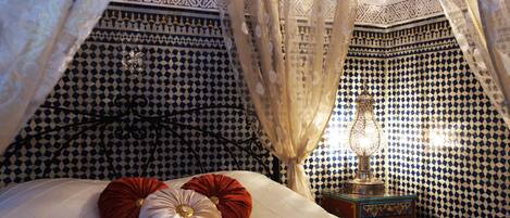 Quarto com parede estampada, cama com almofadas e mesa de cabeceira com abajur.