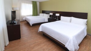 Quarto de hotel com duas camas, uma escrivaninha com abajur e uma televisão.