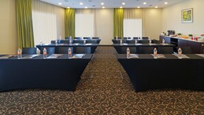 Uma sala de conferência com uma mesa comprida, cadeiras, garrafas de água e um espaço para café.