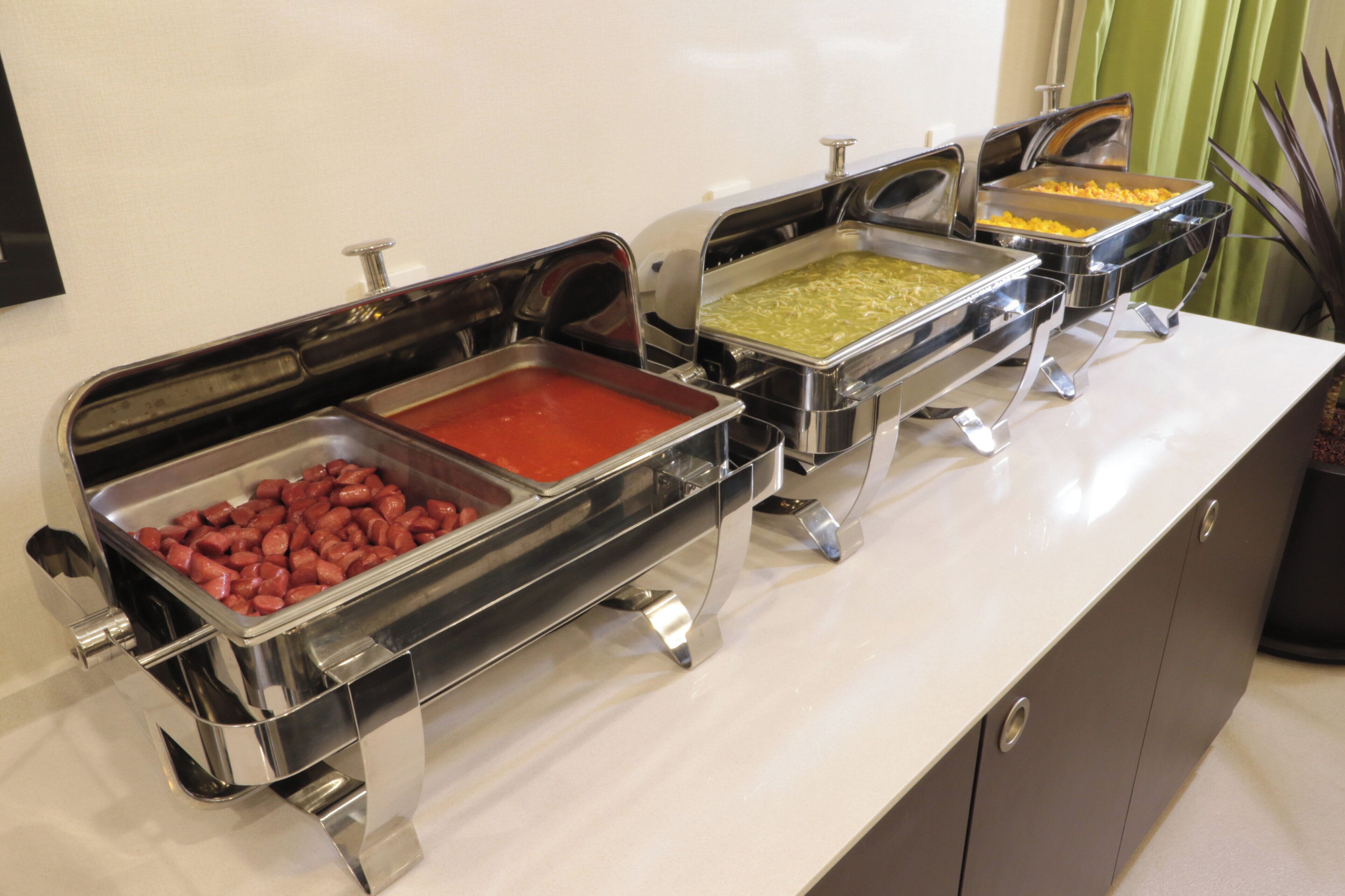 Buffet com diversos alimentos em bandejas de metal.