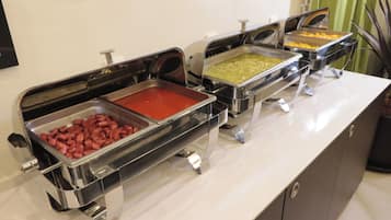 Buffet com diversos alimentos em bandejas de metal.