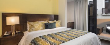 Quarto de hotel com cama, mesa de cabeceira com luminária e telefone, e vista para a varanda externa.
