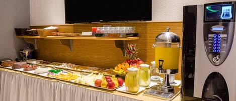 Buffet com diversos alimentos e uma máquina de café.