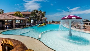 Piscina com uma fonte, palmeiras e vista para a praia.