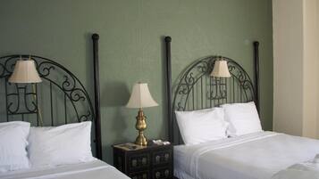 Quarto com duas camas, cada uma com cabeceira e mesa de cabeceira com luminária.